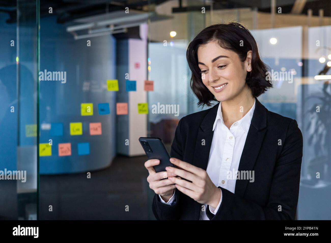 Professional businesswoman in office uses smartphone for communications ...