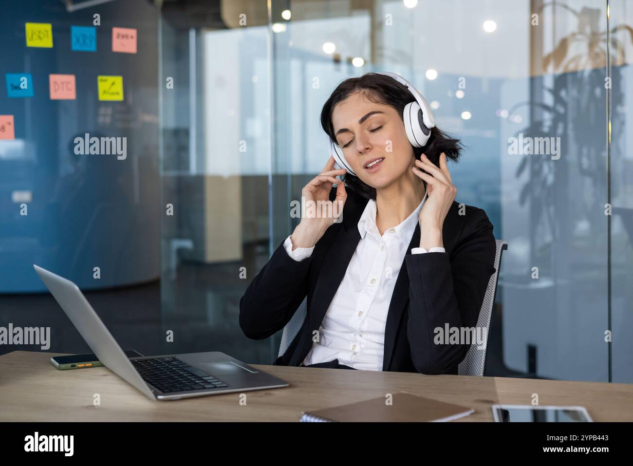 Businesswoman in modern office wearing headphones while working on ...
