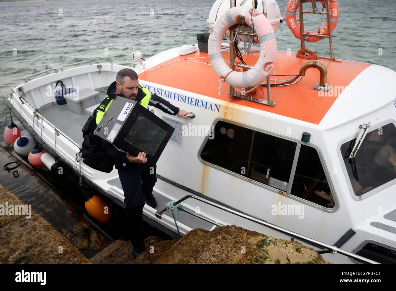 Garda Ronan Steede carries the ballot box that is taken by boat to the ...