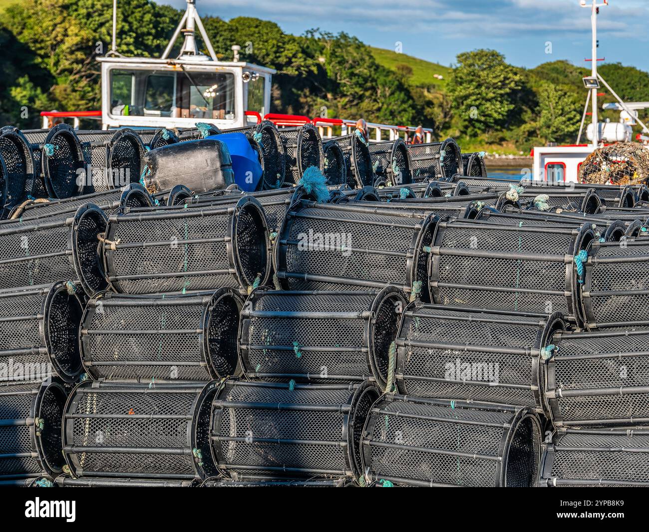 A large pile of fishing nets and traps is stacked by the riverside ...