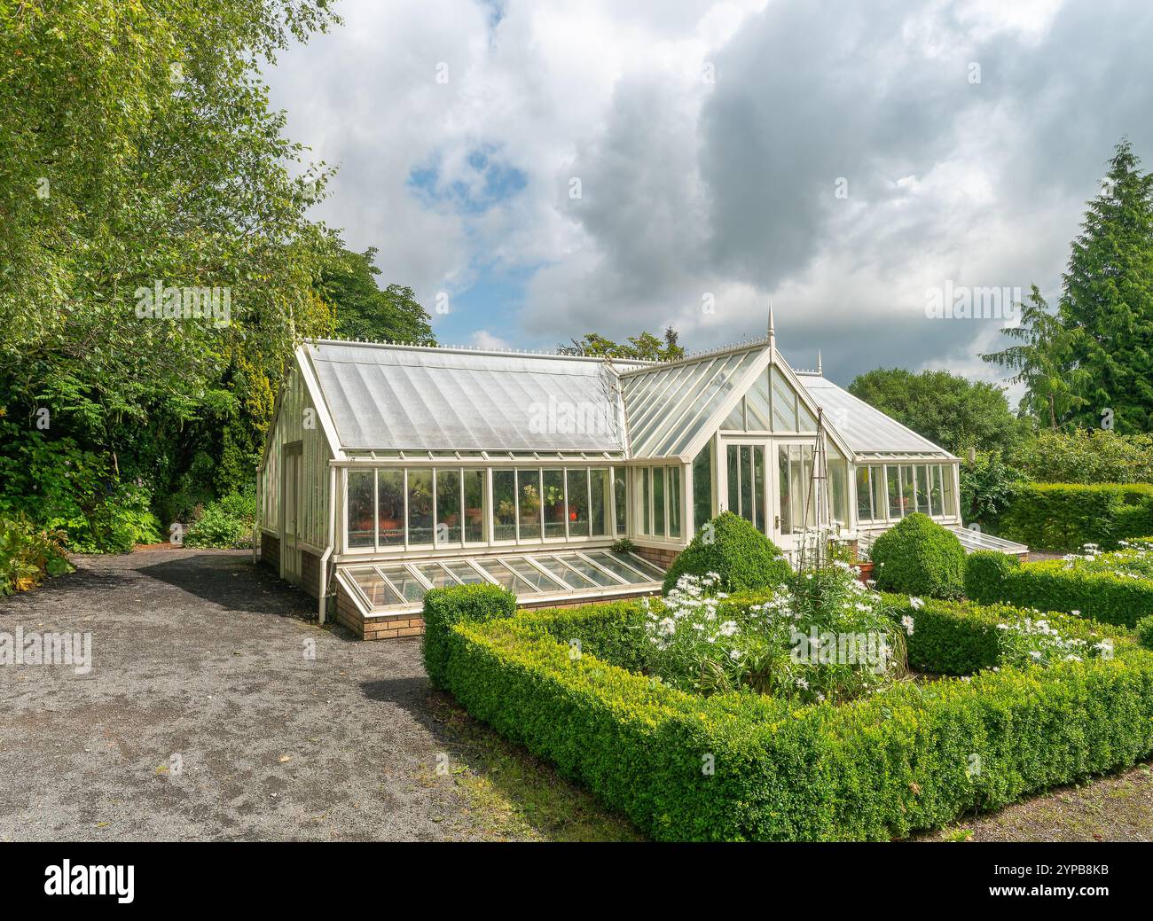 A grand stone building is framed by lush trees and greenery, under a ...