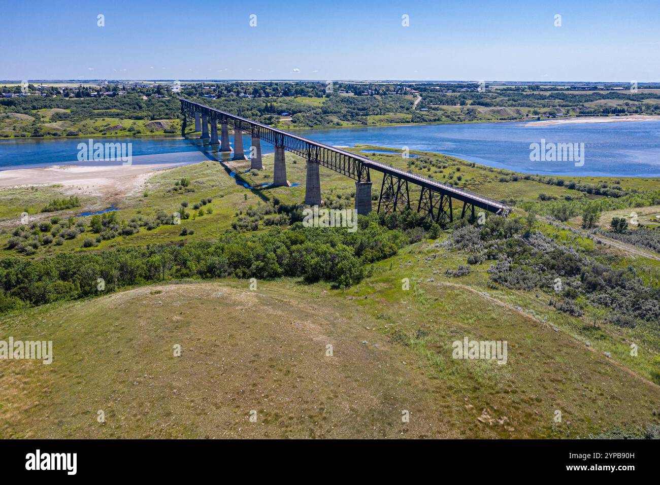 A bridge spans a river, with a city in the background. The bridge is a ...
