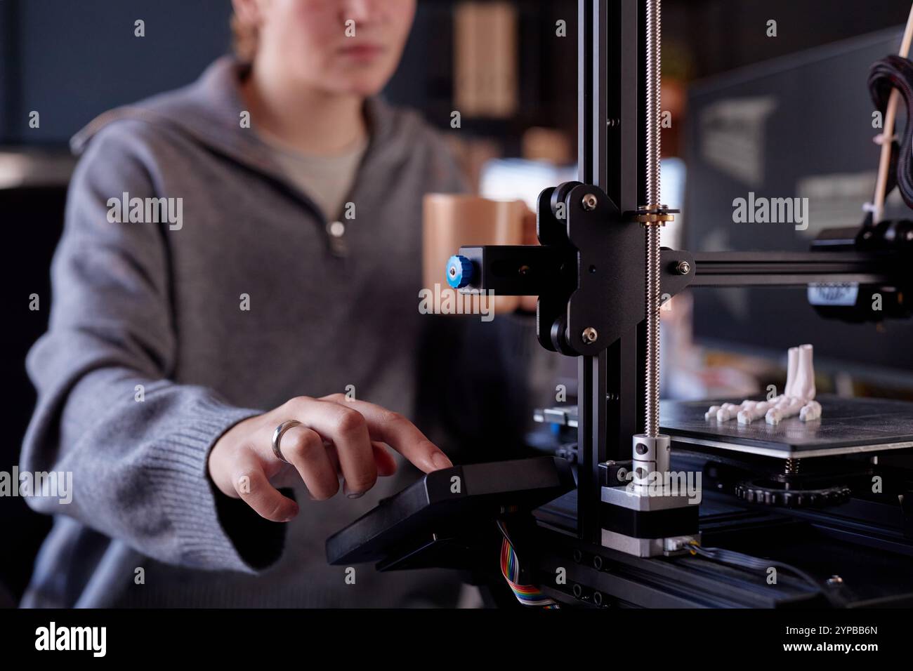 Person using 3D printer in modern workspace, concentrating on machine ...