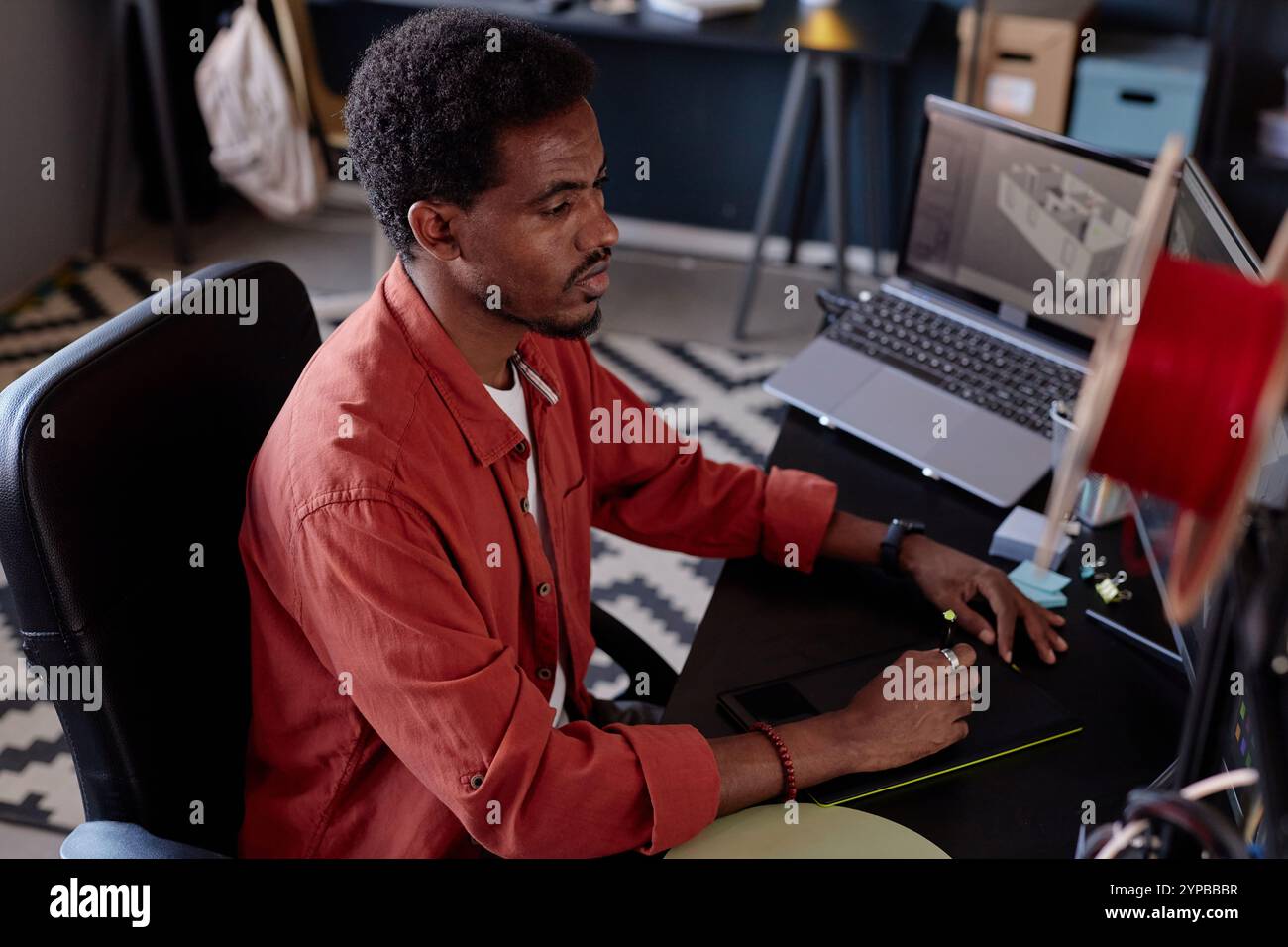 Man sitting at a desk with CAD software on screen, creating intricate ...