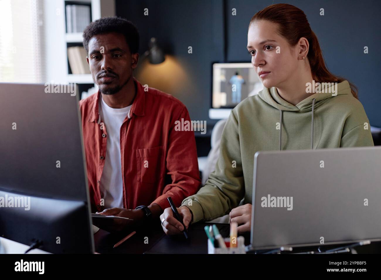 Colleagues focusing on a project using laptops in a modern office with ...