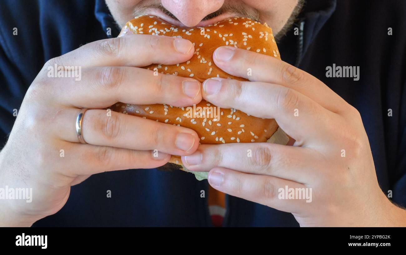 Hanover, Germany. 29th Nov, 2024. ILLUSTRATION - A man eats a Burger ...