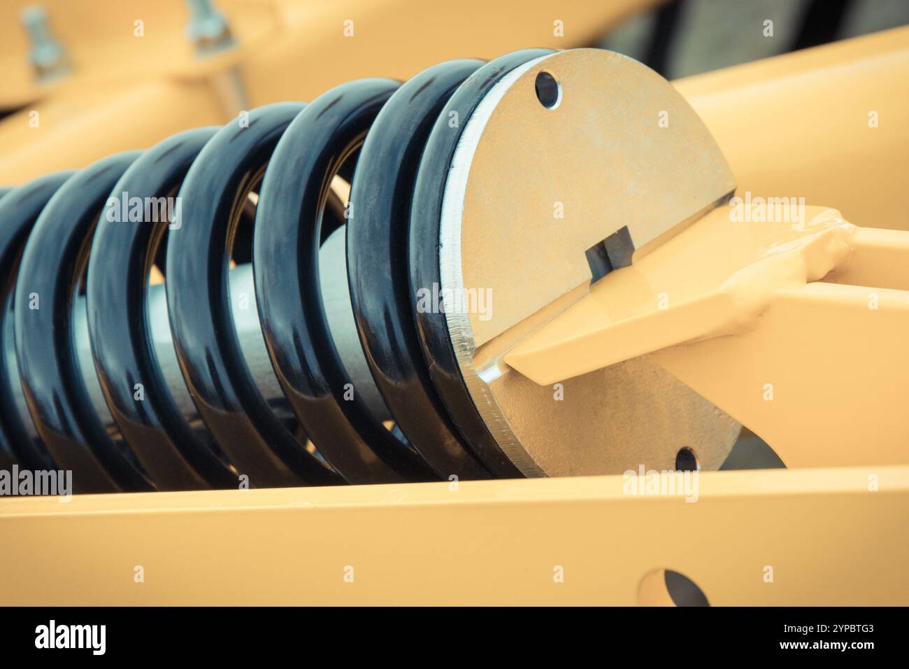 Black hard spring made of steel. Detail and part of big yellow ...