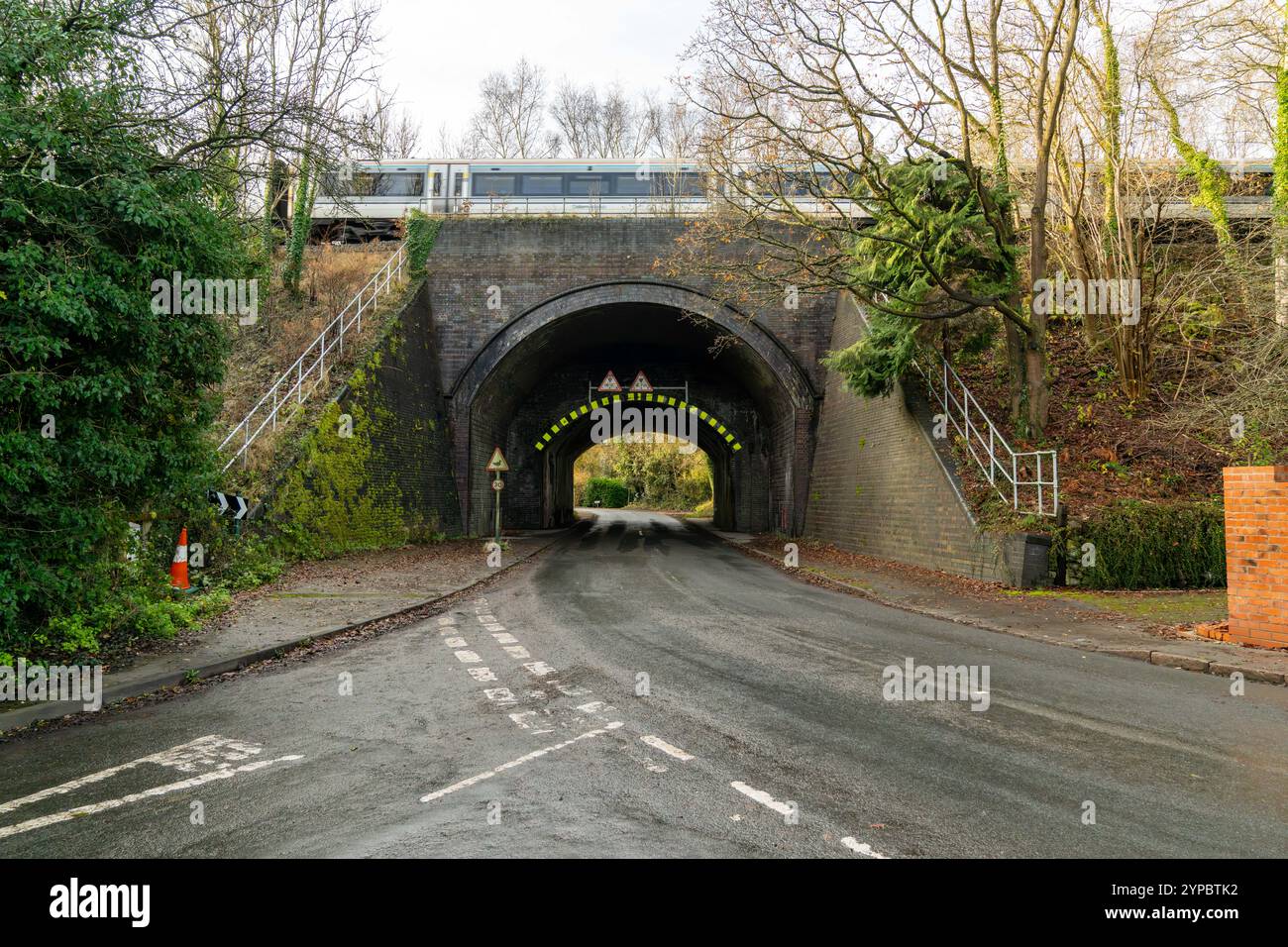Commuter train passing over a narrow road bridge in the british ...
