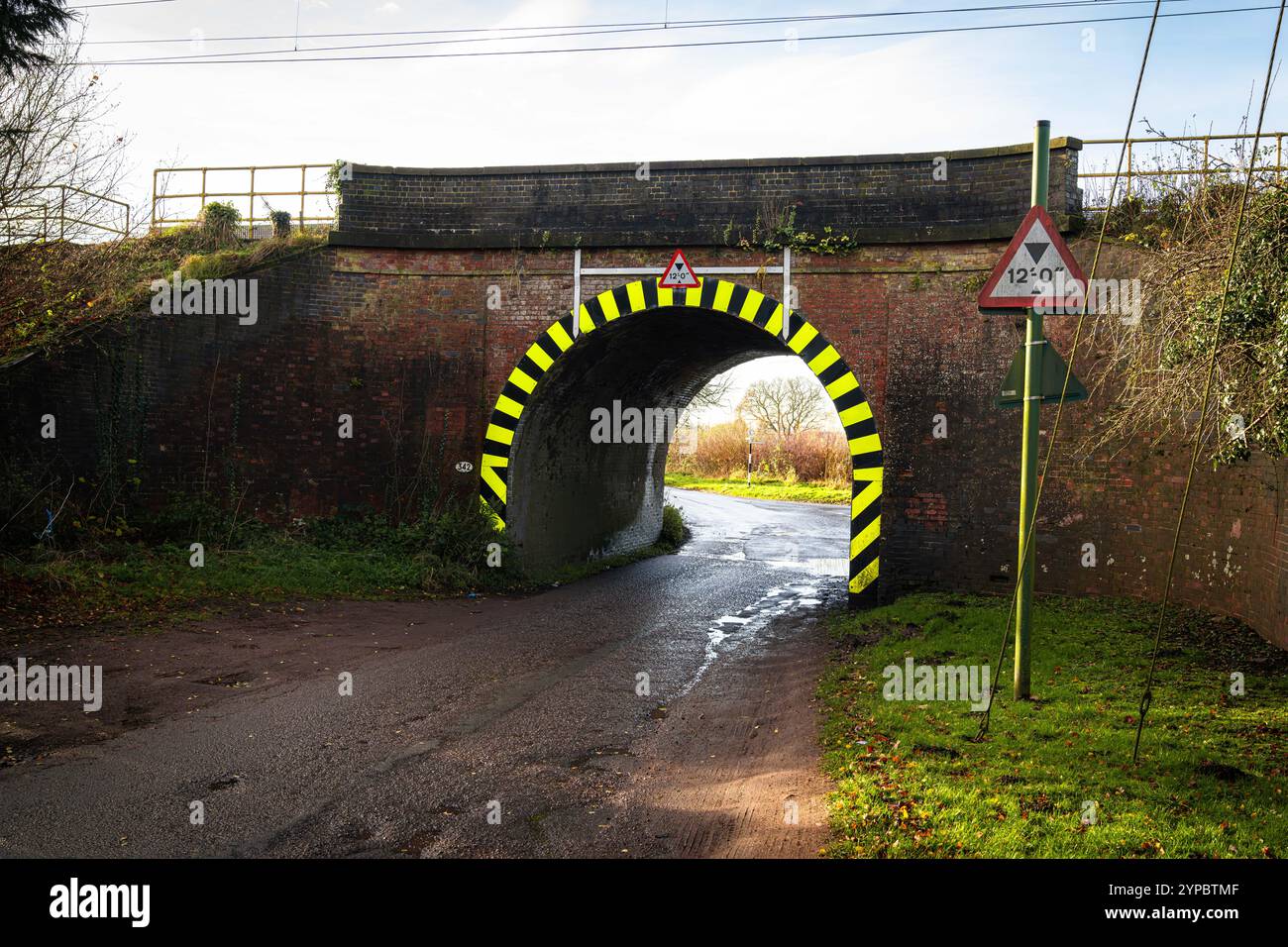 Narrow country road passing under a low railway bridge with height ...