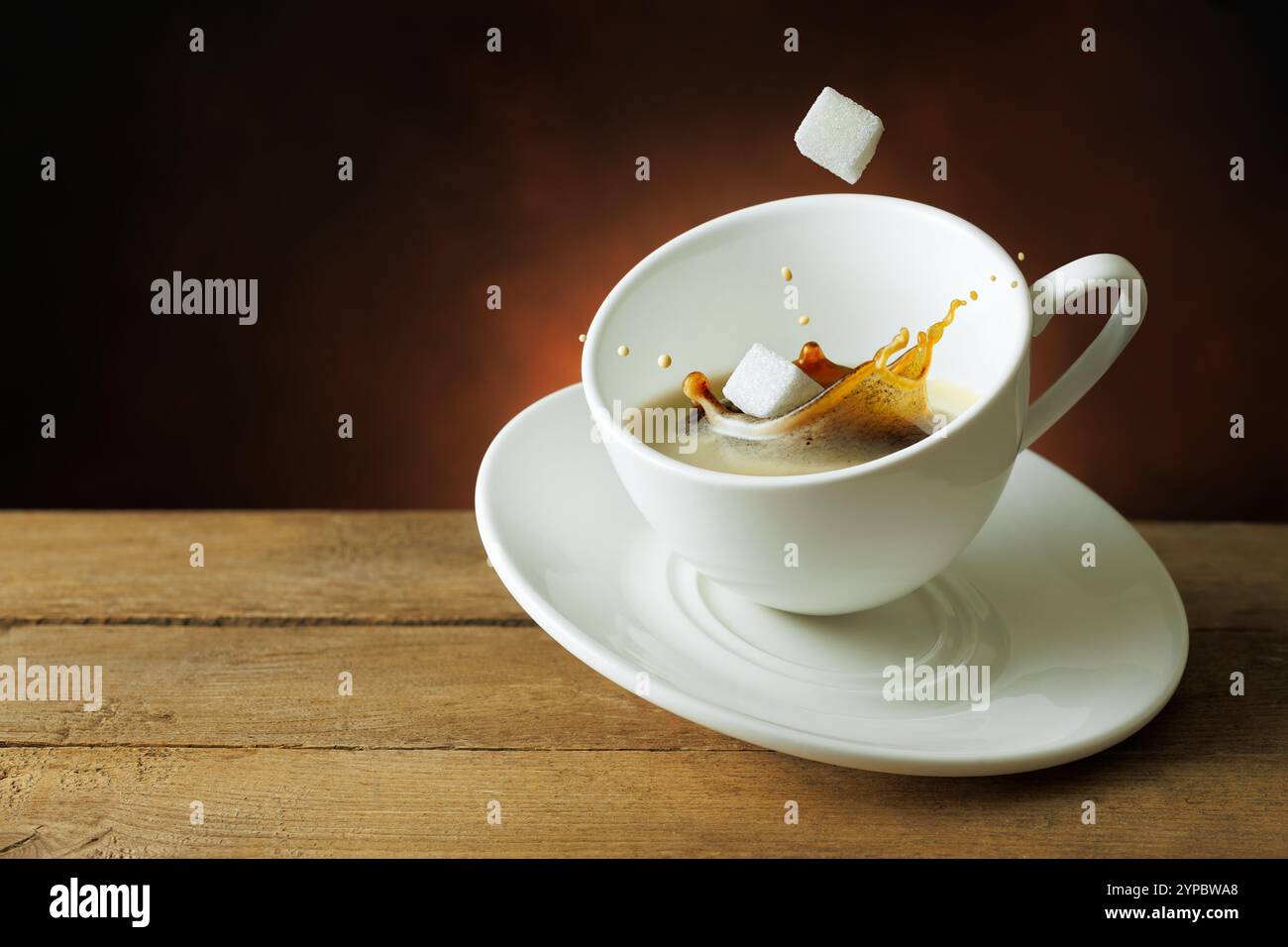 sugar cubes falling into flying cup of coffee with splashes on table ...