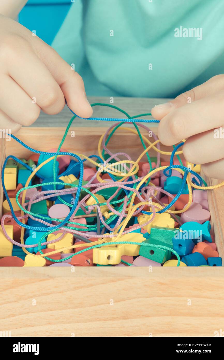 Hands of baby playing thread and wooden colorful beads used to making ...