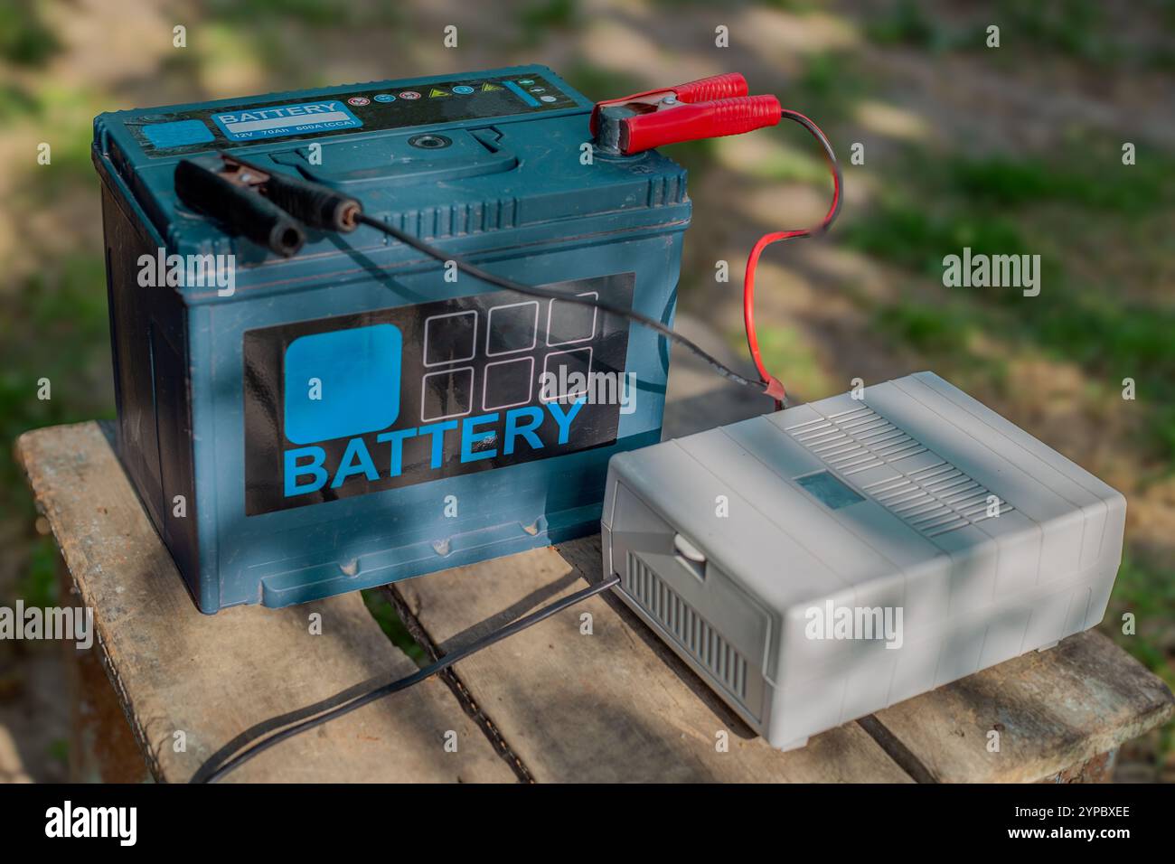 Charging a car battery with a stationary charger. The clamps are ...