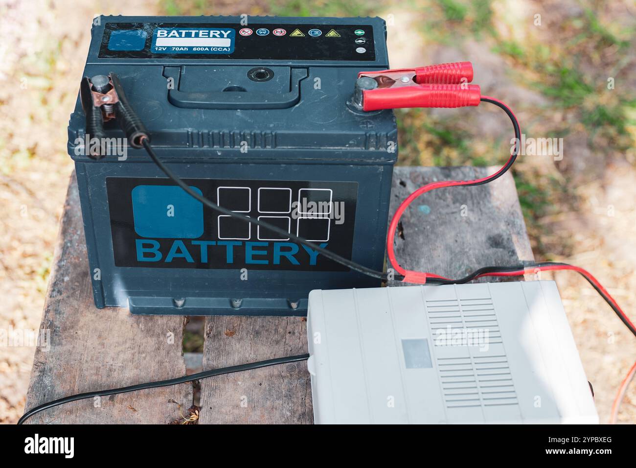 Charging a car battery with a stationary charger. The clamps are ...