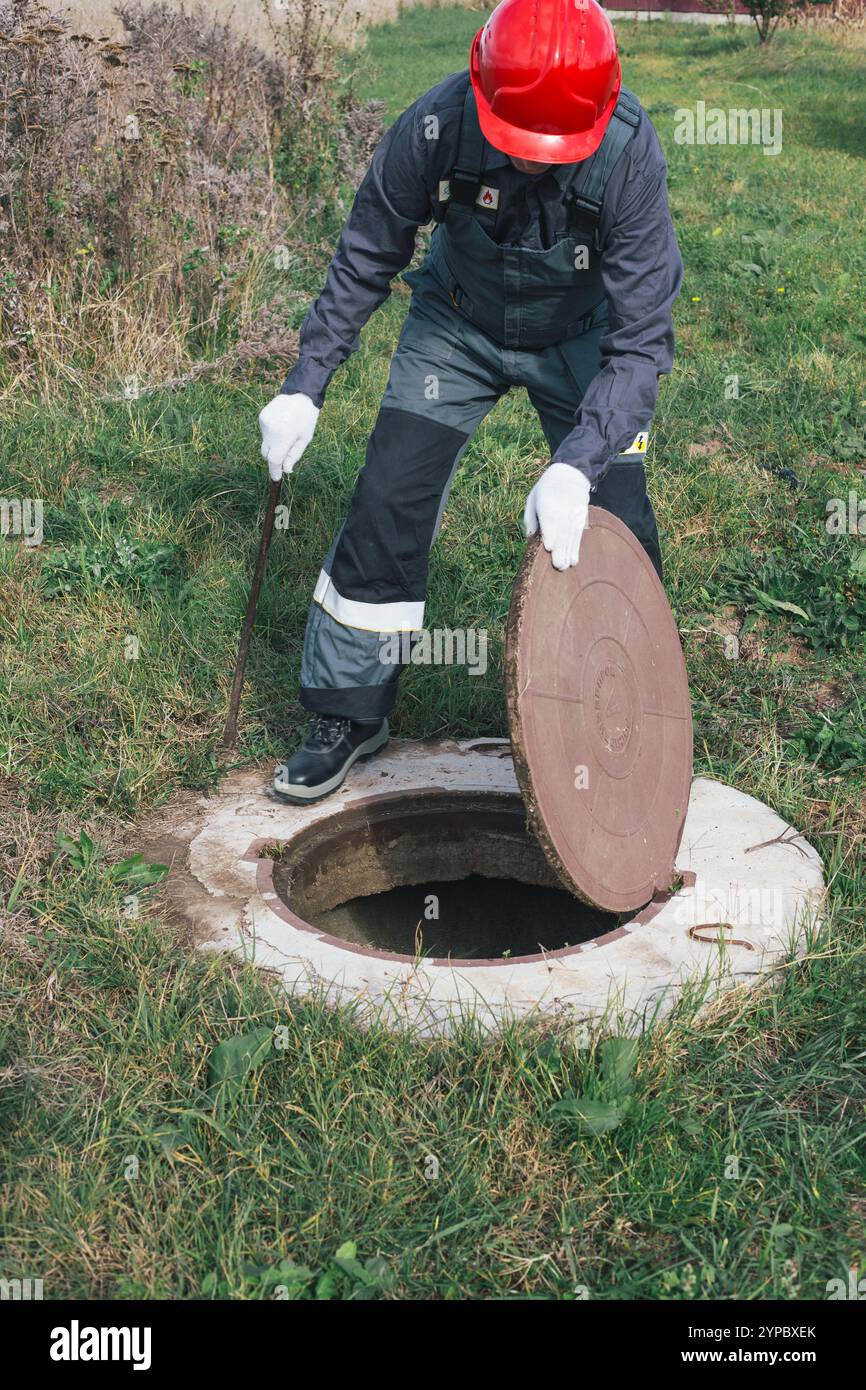 Worker opens septic well manhole cover. septic tank maintenance and ...