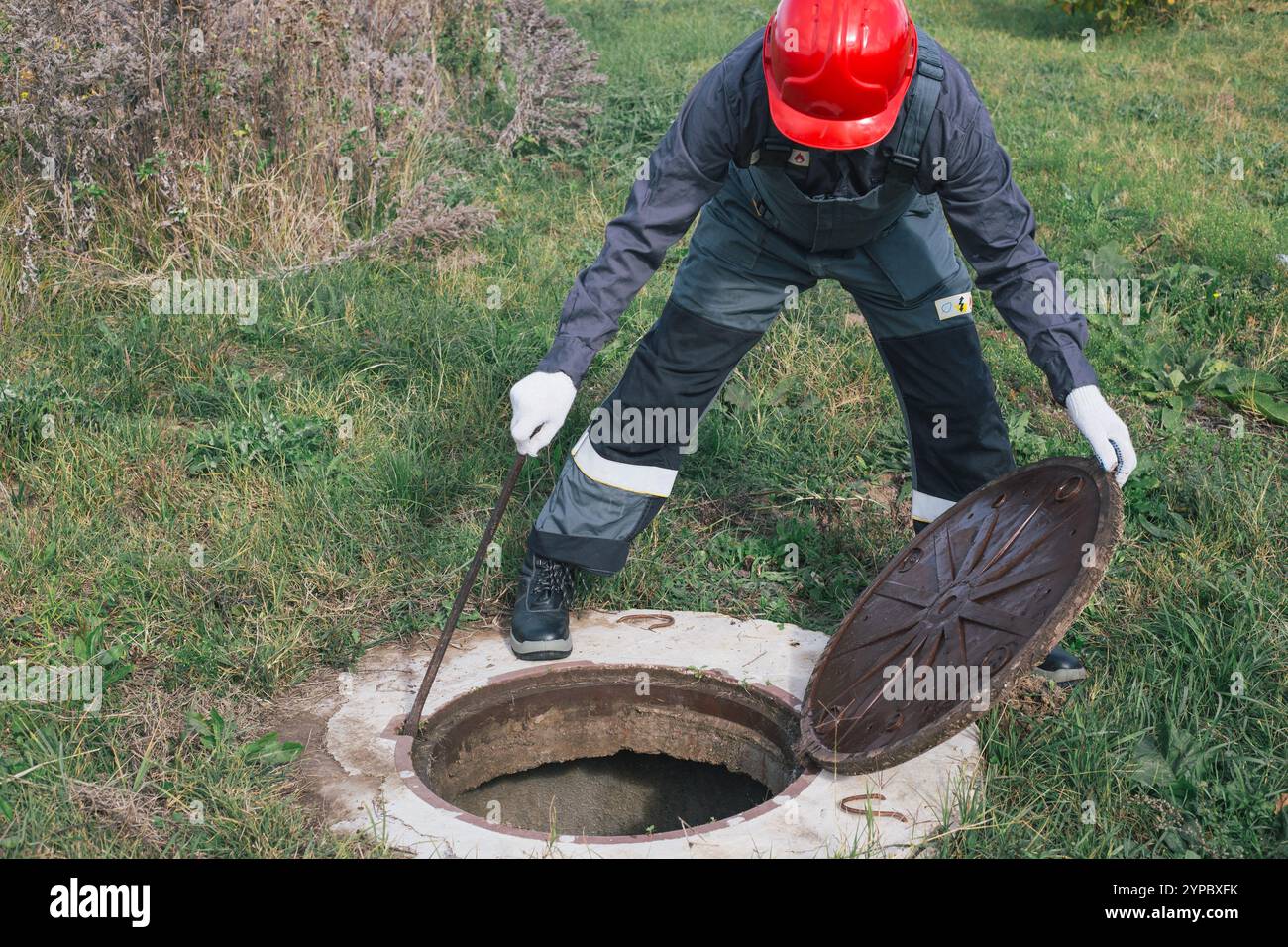 Worker opens septic well manhole cover. septic tank maintenance and ...