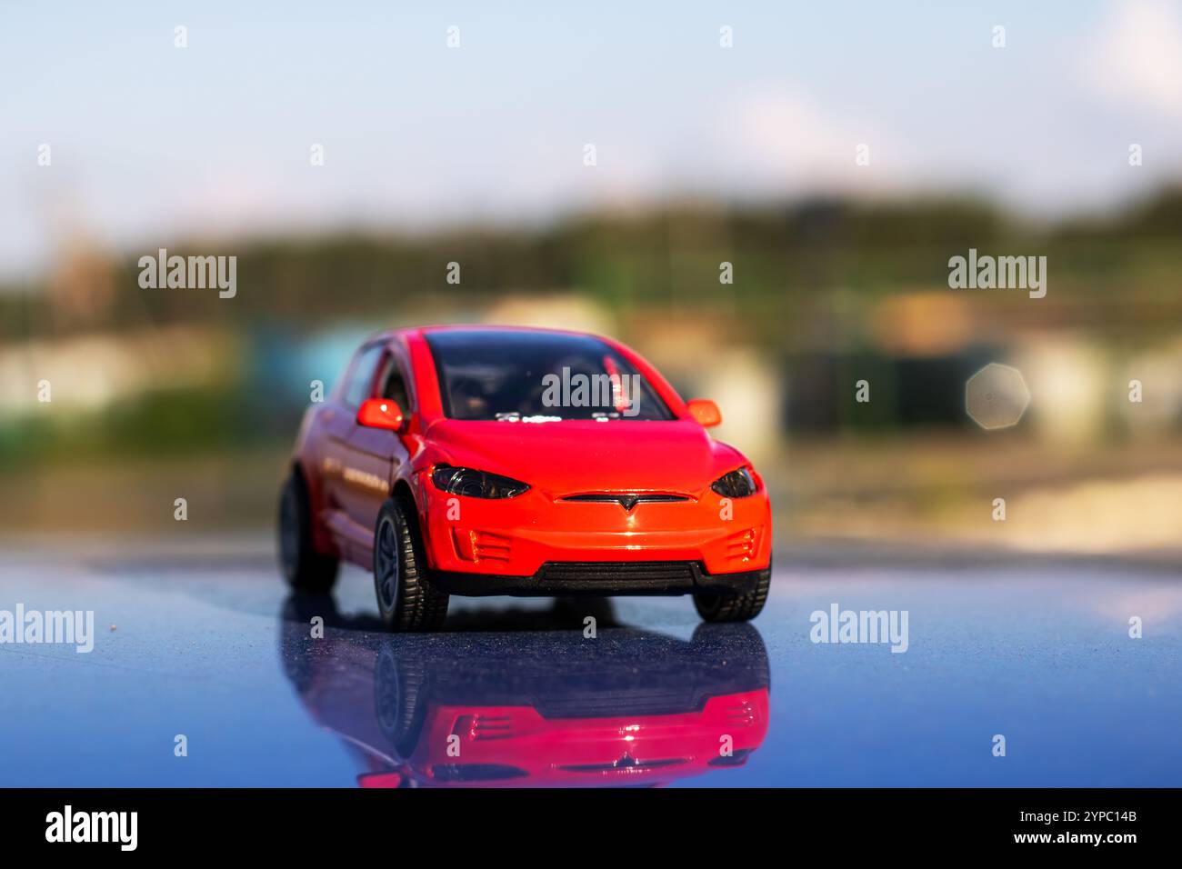 A bright red toy car is parked on a smooth, vibrant blue surface ...