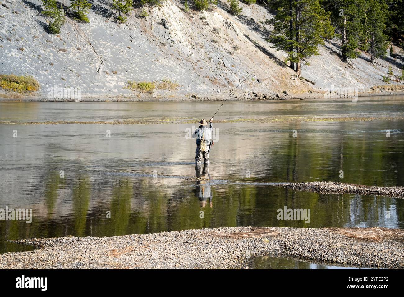 a fly fisherman in waders fishing in a blue water river Stock Photo - Alamy