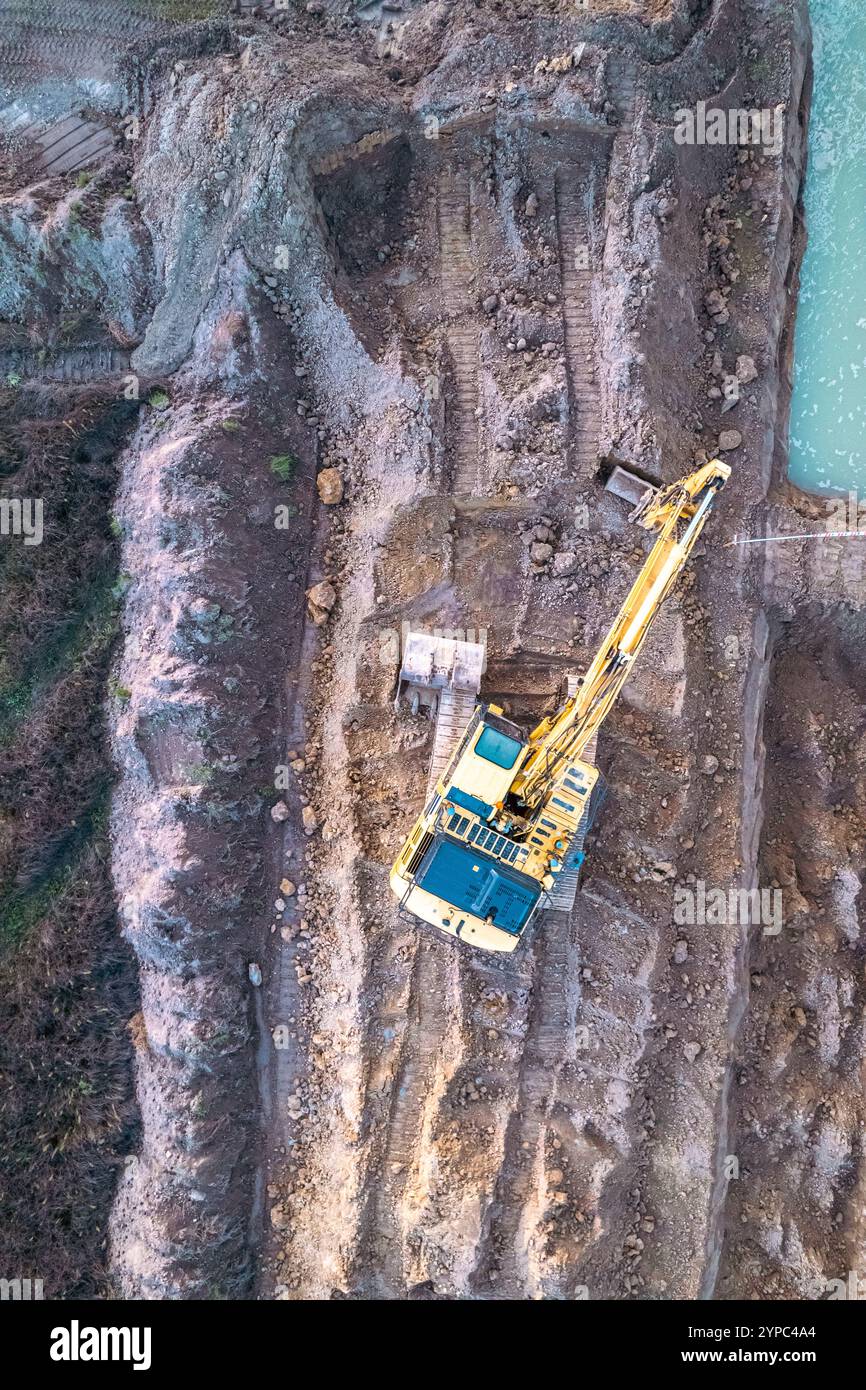 zenithal aerial drone view of an excavator machine digging a trench in ...