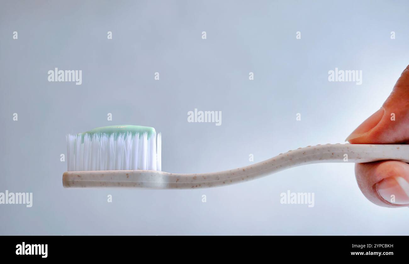 A hand holding eco toothbrush with squeezed toothpaste on top, close up ...