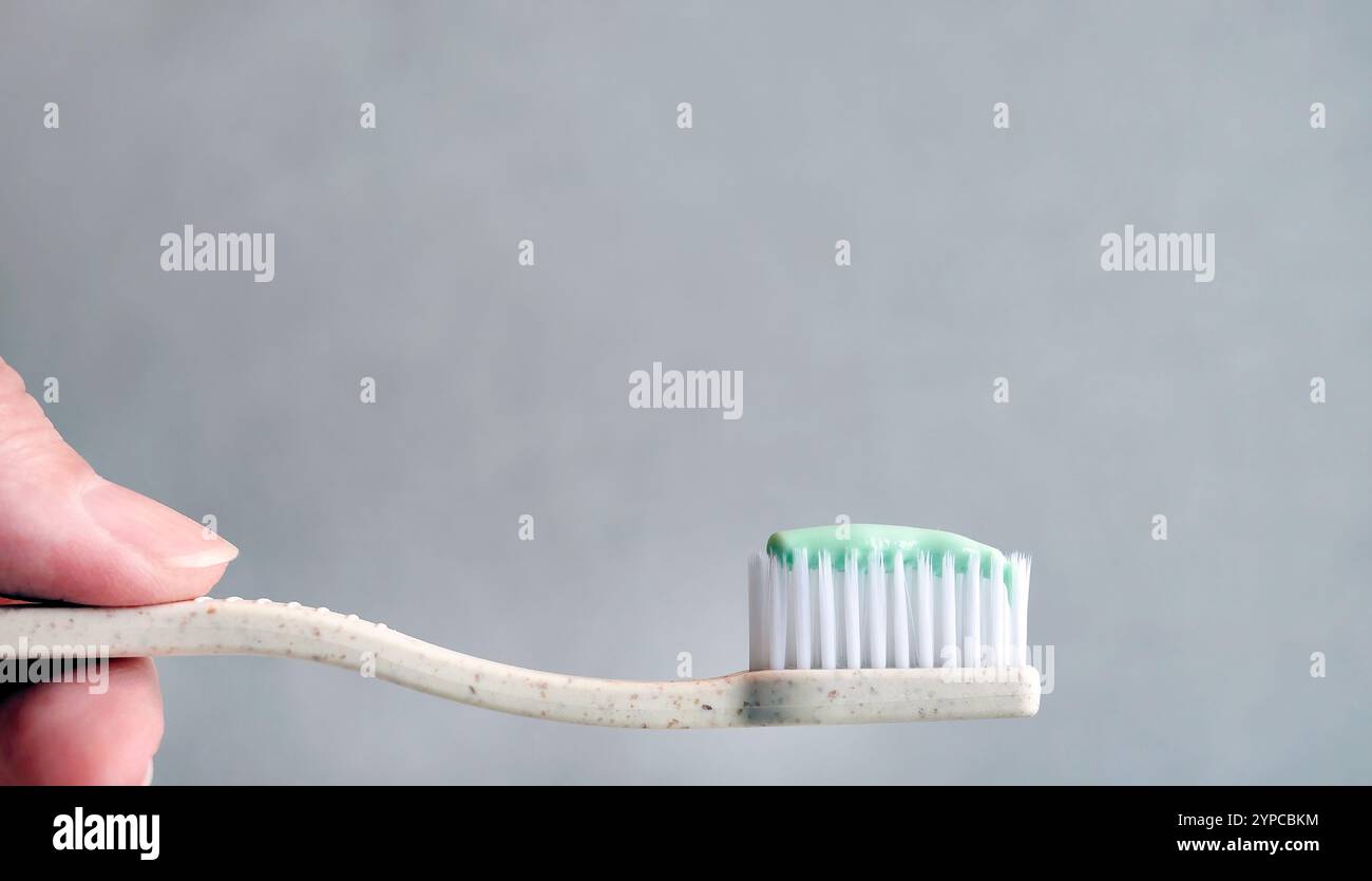 A hand holding eco toothbrush with squeezed toothpaste on top, close up ...