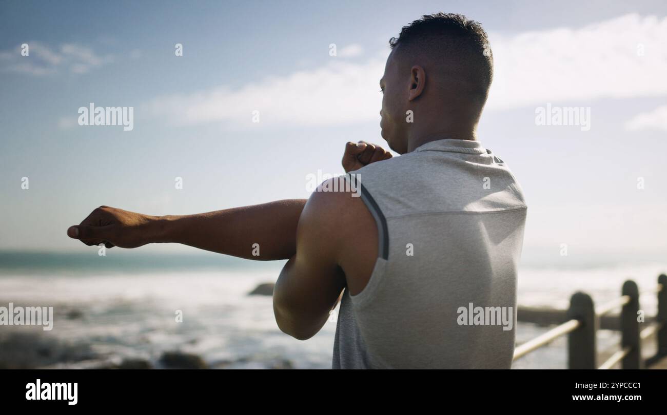 Seaside, man and arm stretching for fitness with warm up for exercise ...