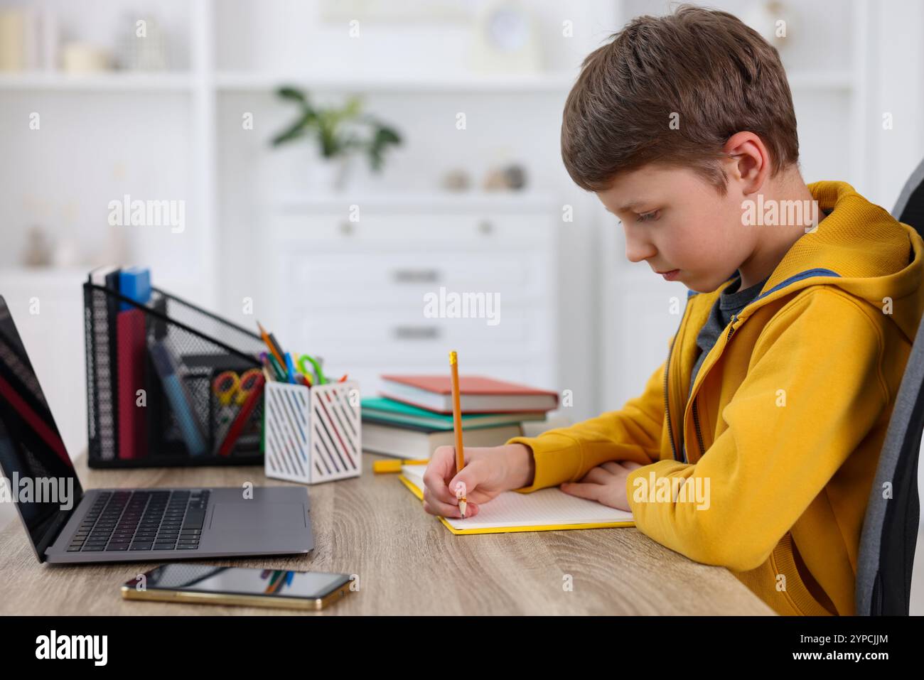 Boy with correct posture doing homework at wooden desk indoors Stock ...