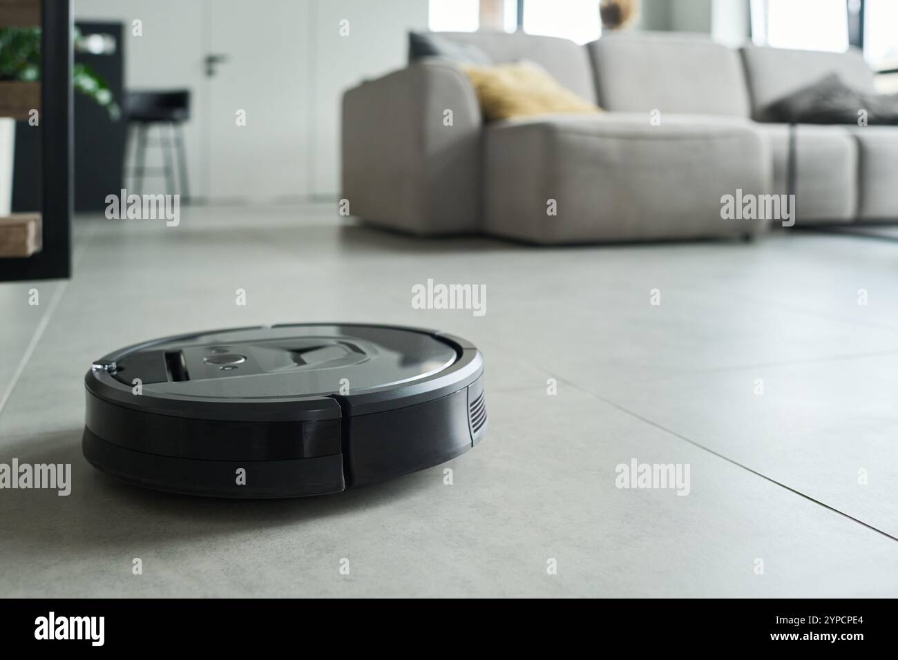 Robotic vacuum cleaner moving across tiled floor of modern living room ...