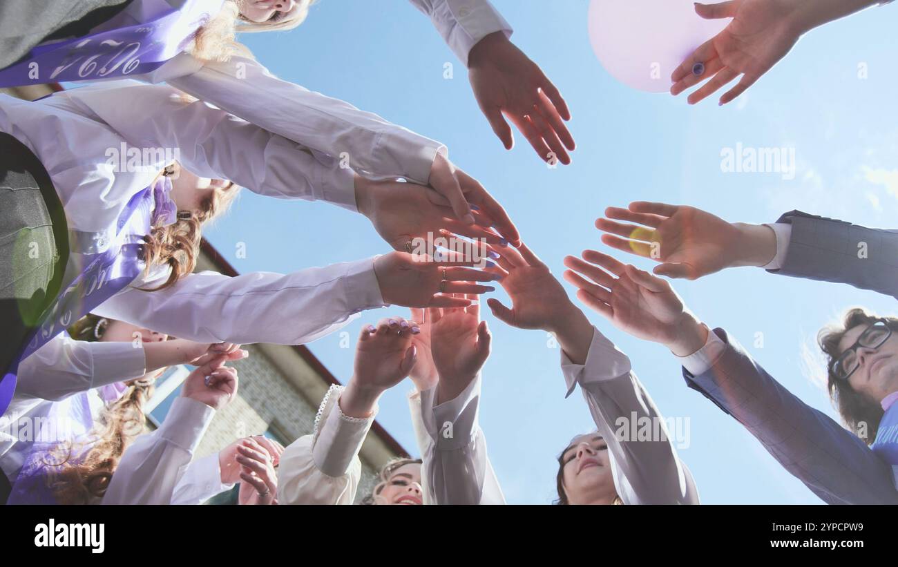 Students linking arms and holding balloons to celebrate their ...