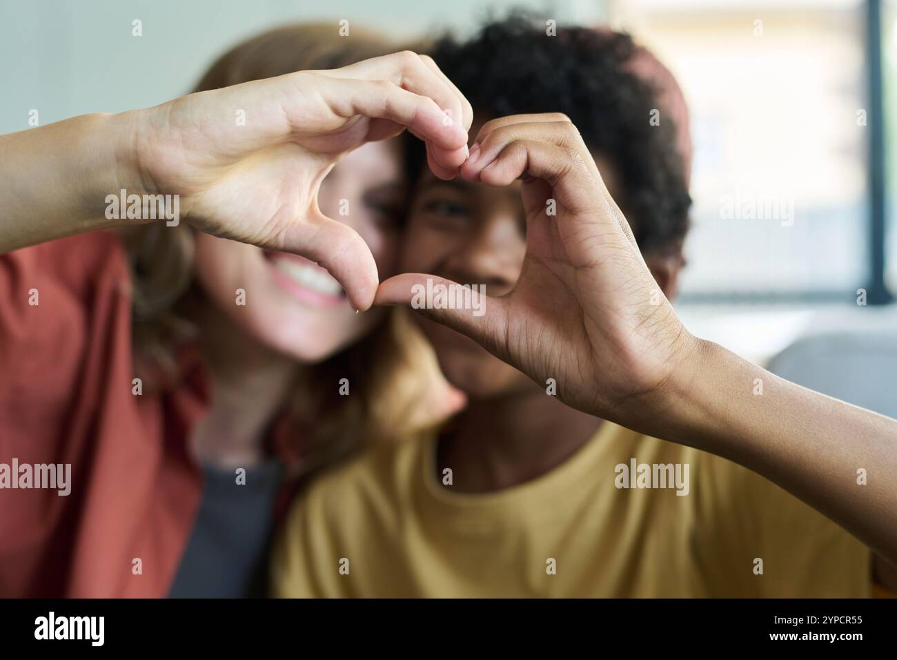 Close-up of two people of different races forming heart shape with ...