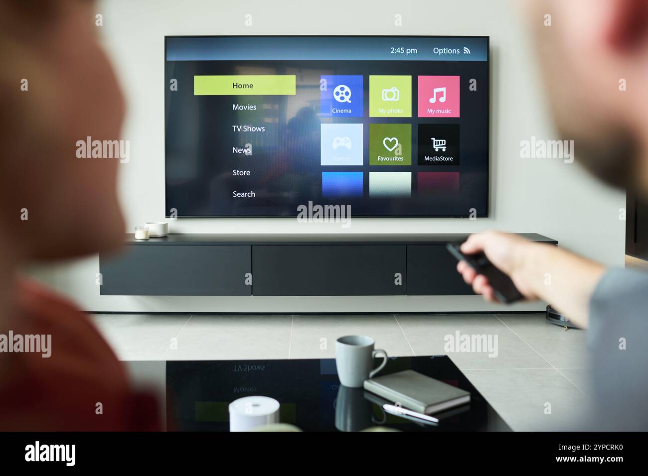 Two people using remote control while seated and facing smart TV ...