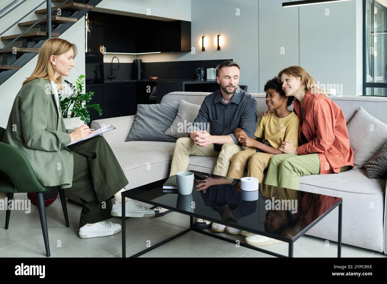 Family sitting on couch discussing important matters with counselor in ...