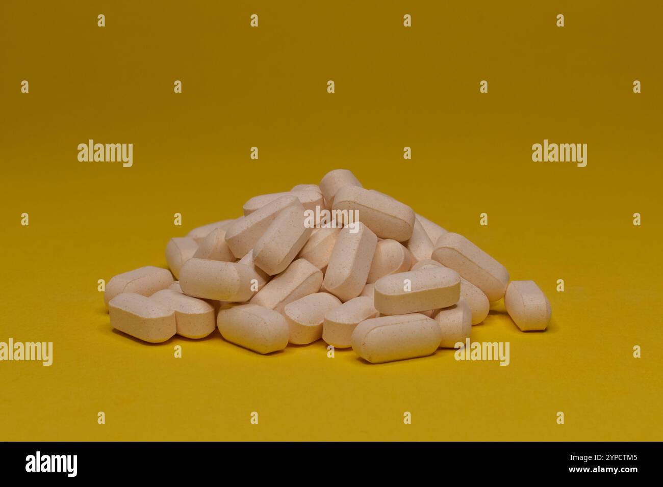 Pile of vitamin tablets on a yellow background, winter supplementation ...