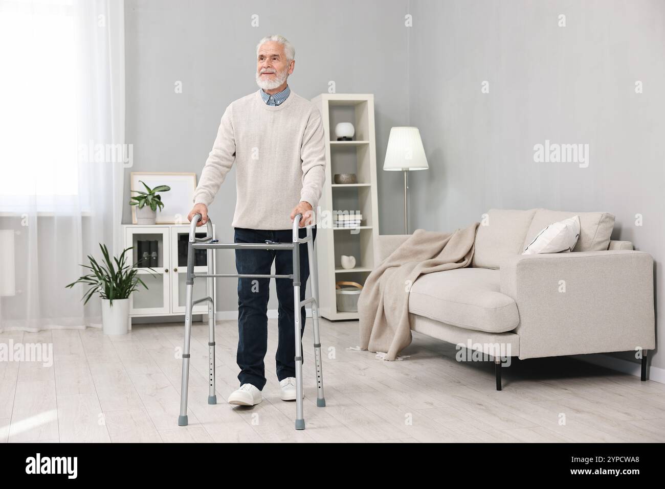 Senior man using walking frame at home Stock Photo - Alamy