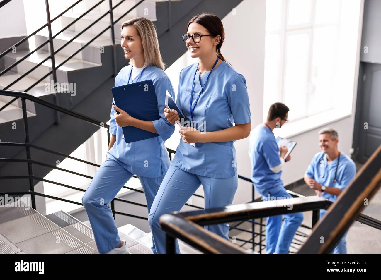 Healthcare workers with tablet and clipboard walking up stairs in ...