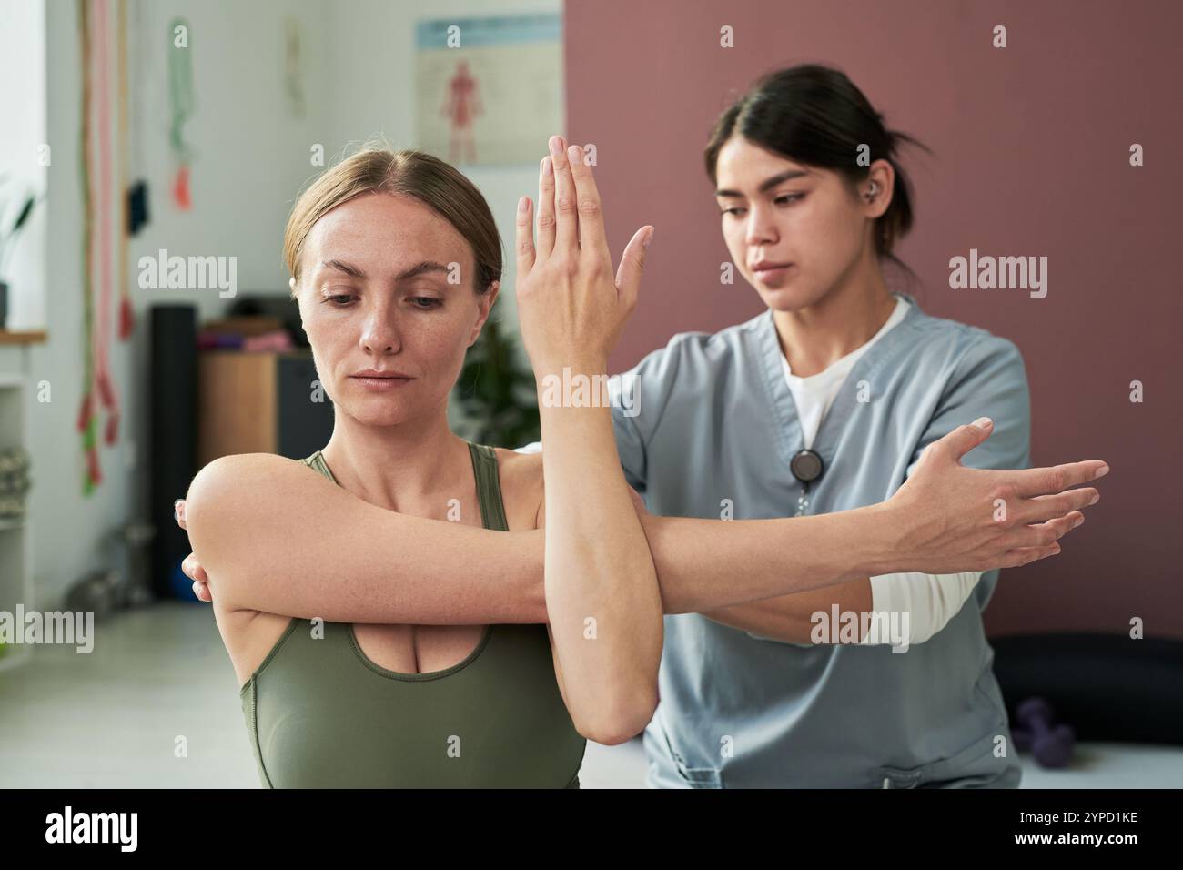 Yoga instructor guiding student through a stretching exercise in a ...