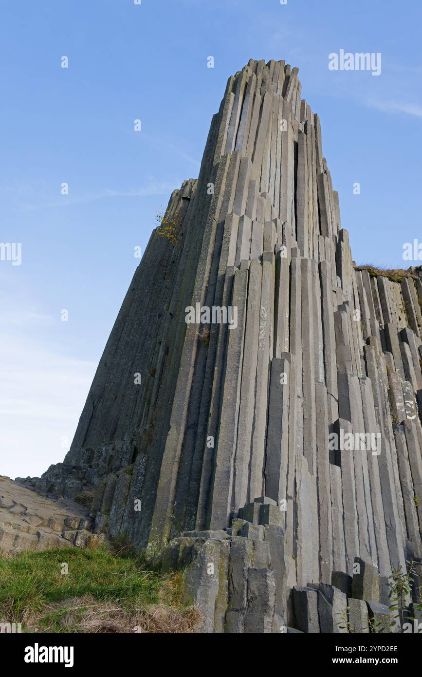 Towering, steep basalt formation rises under the clear sky, manor house ...