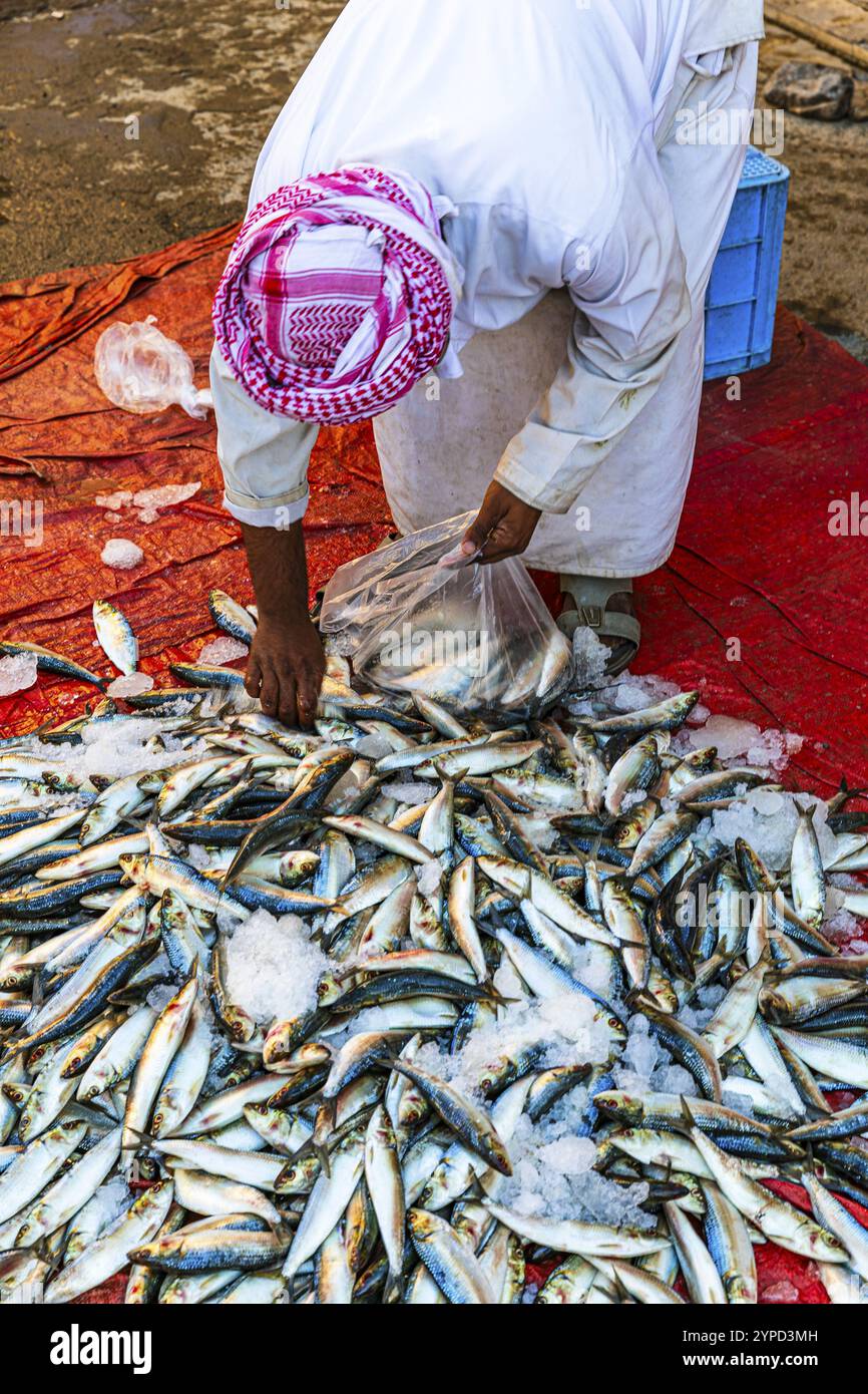 An Omani in traditional dress buys fish at the weekly market market in ...