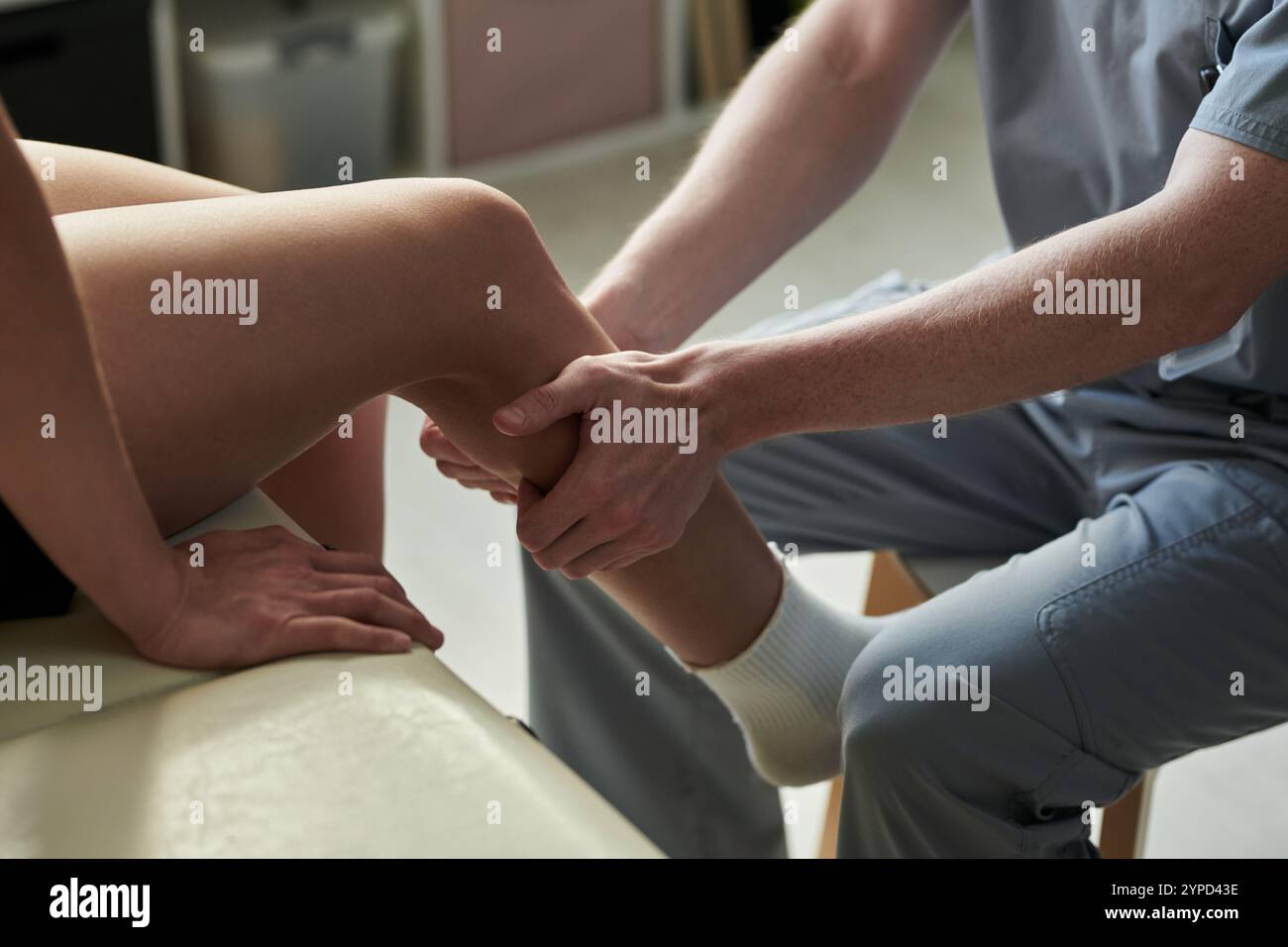 Medical professional examining patient's knee in clinic setting showing ...