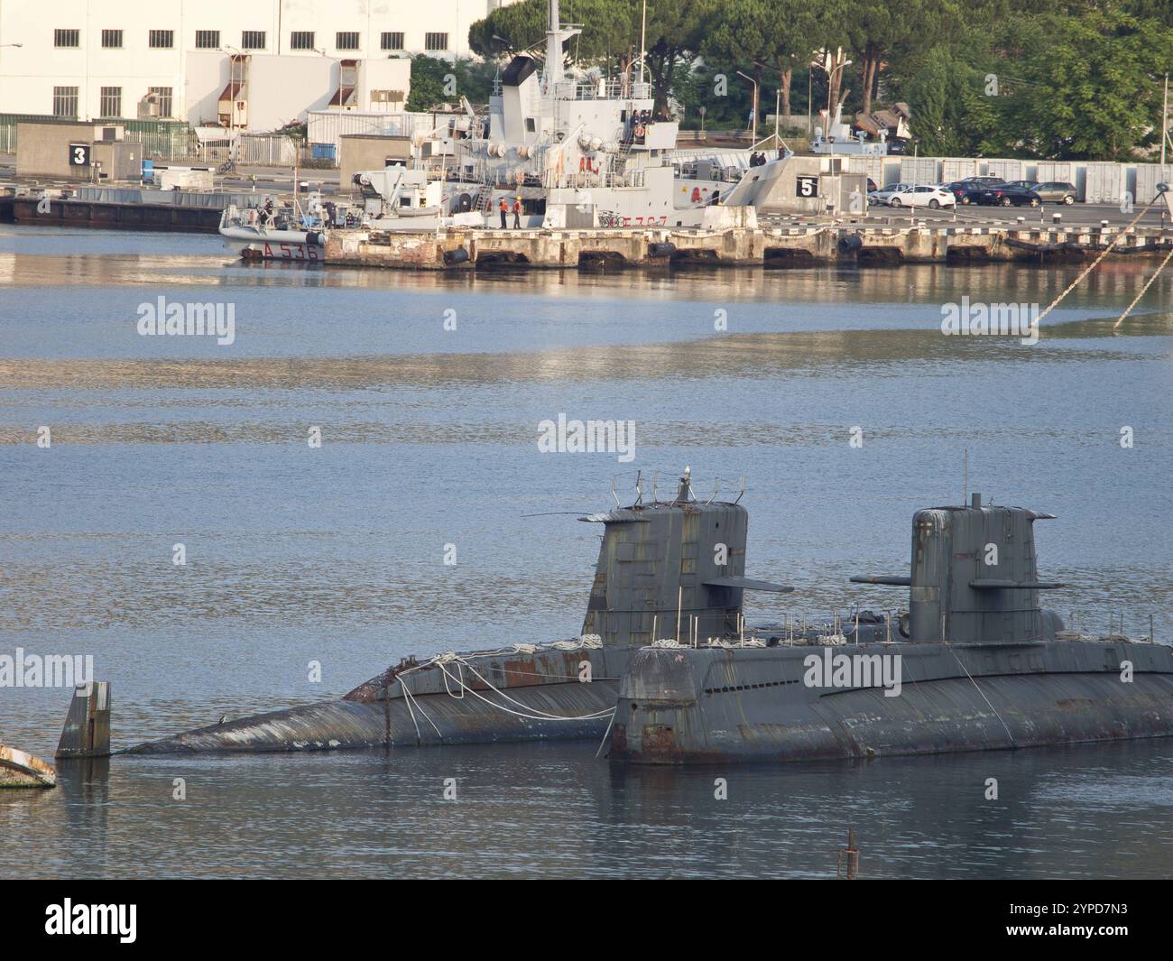 Old submarines in an industrial-looking harbour with surrounding ...