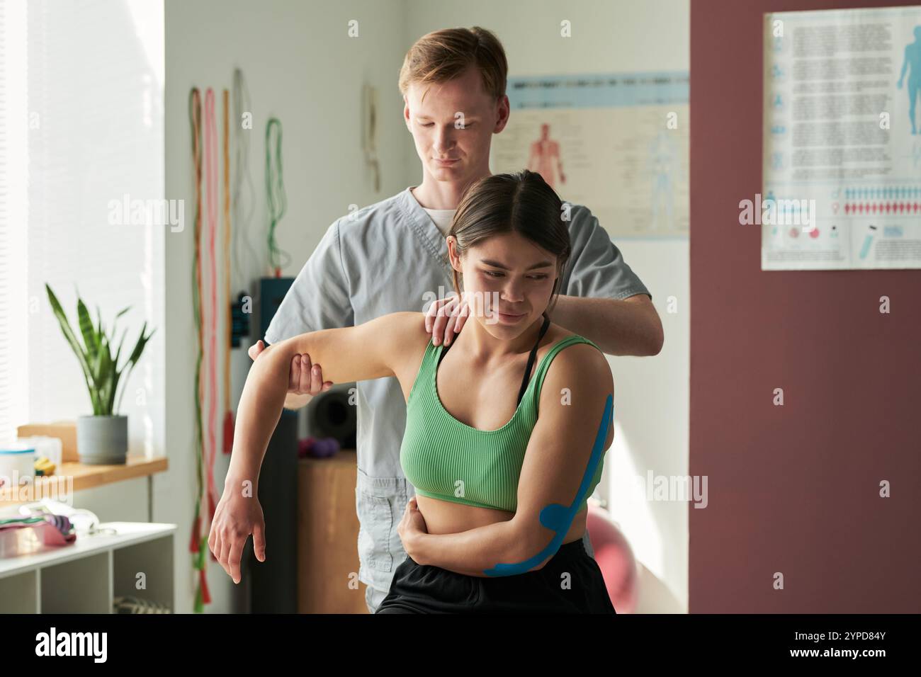 Assisting woman in a physical therapy session, focusing on her shoulder movements and ...
