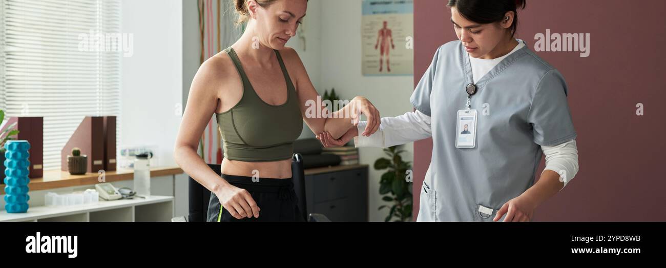 Physical therapist wearing uniform assisting woman during ...