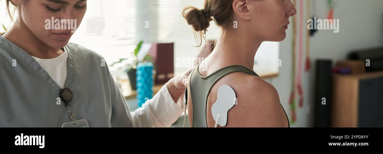 Medical professional placing electrode pad on patient's upper back in ...