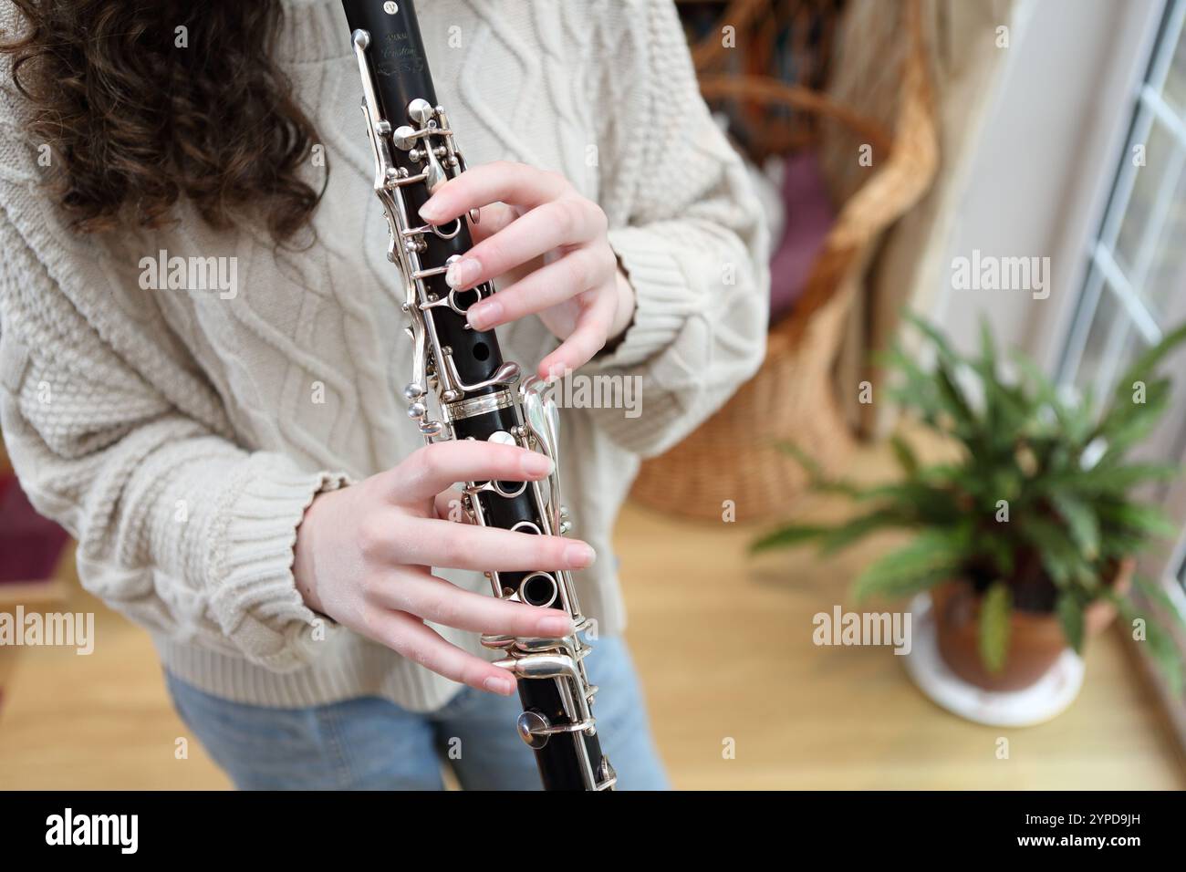 Teenage girl playing clarinet in living room close up of tone holes and ...