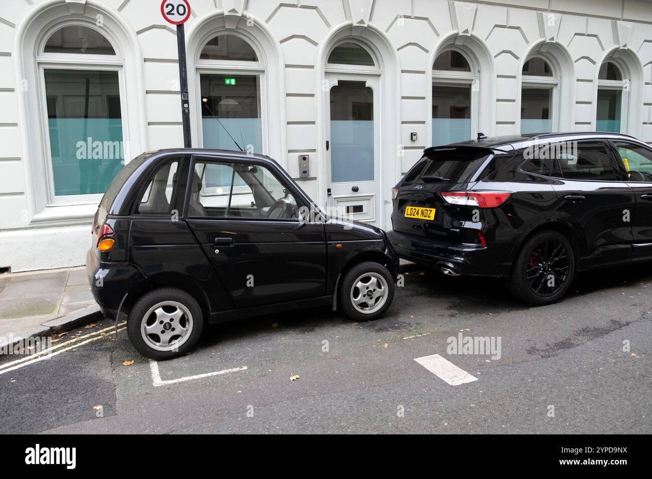 Small black fuel efficient car squeezed into a tiny parking space in ...