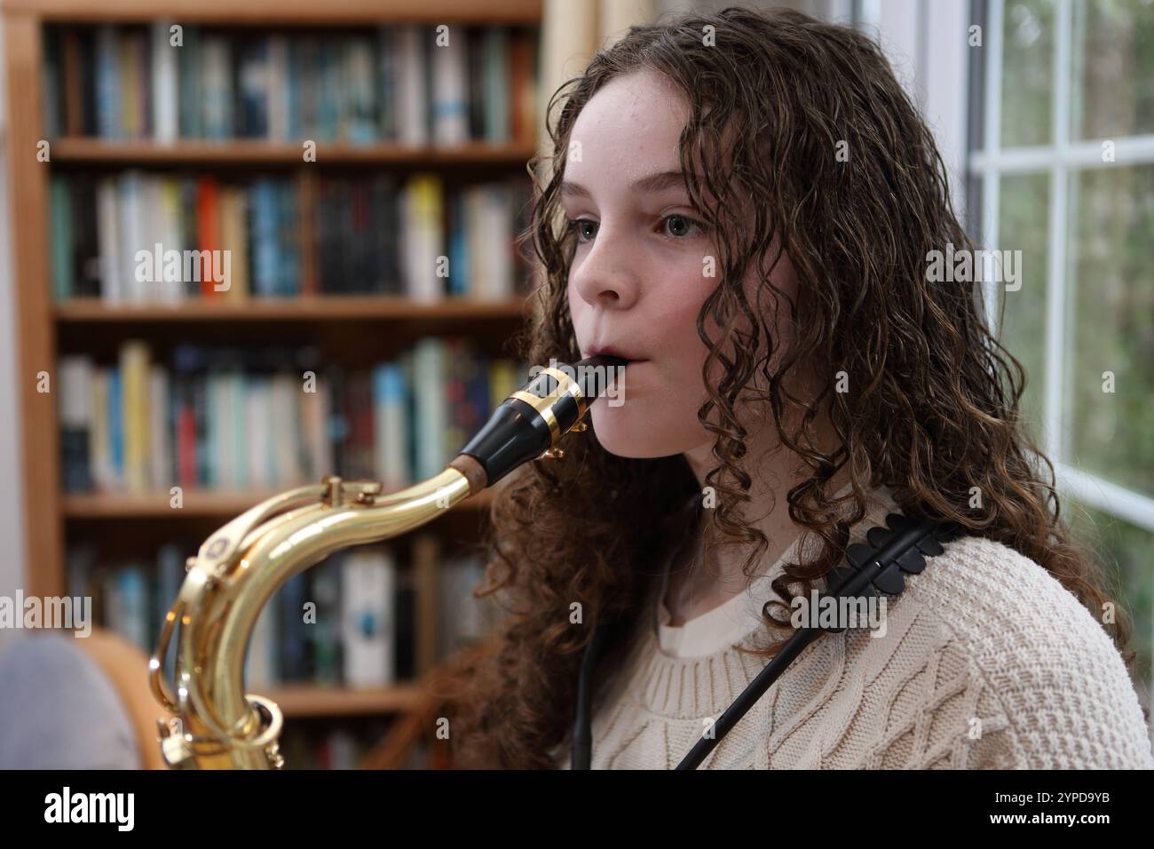 Teenage girl playing saxophone in living room Stock Photo - Alamy