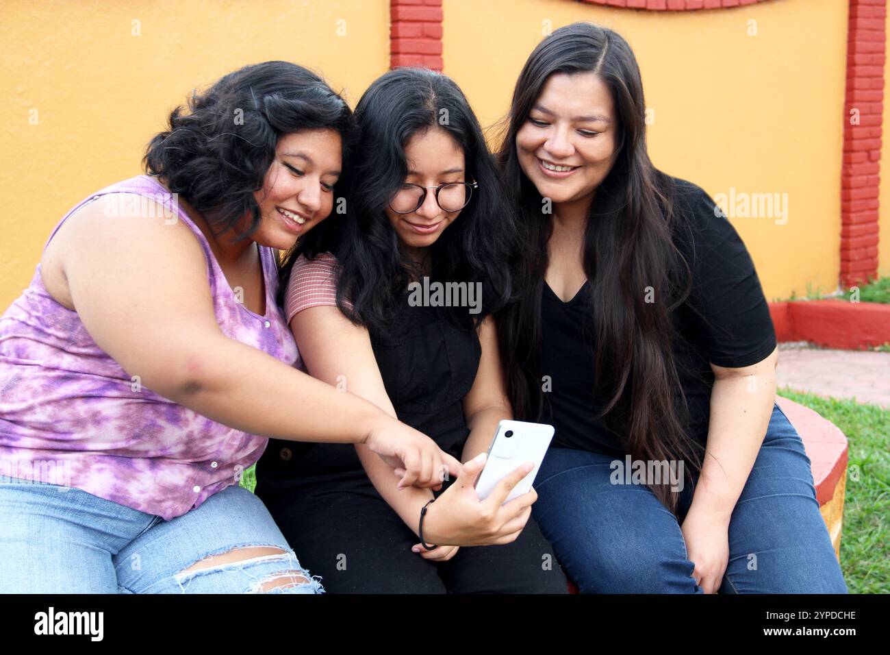 Three brunette Latin women use cell phones to make video calls and take ...