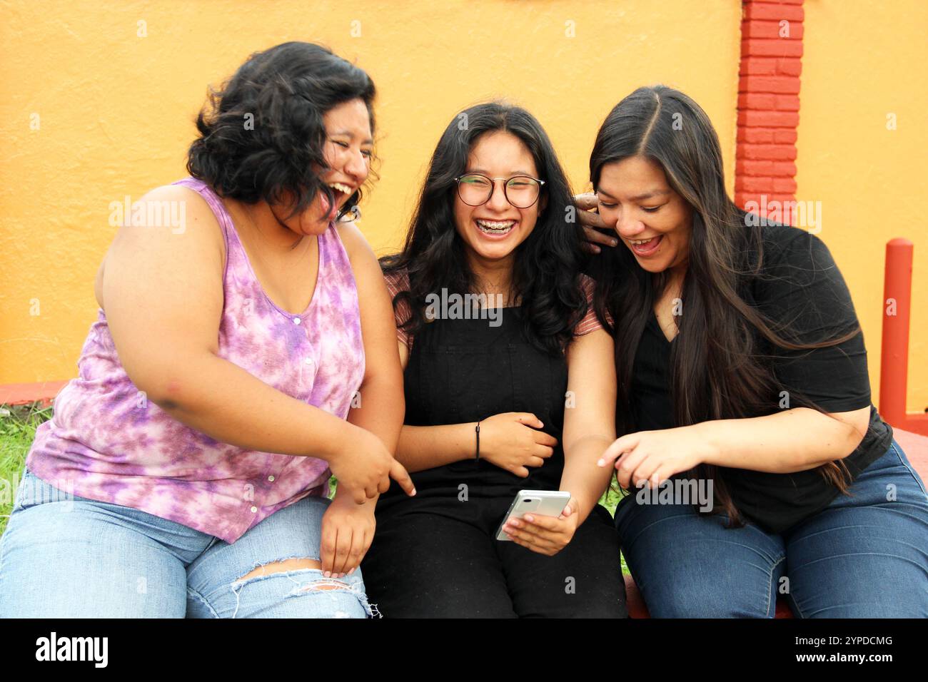 Three brunette Latin women use cell phones to make video calls and take ...