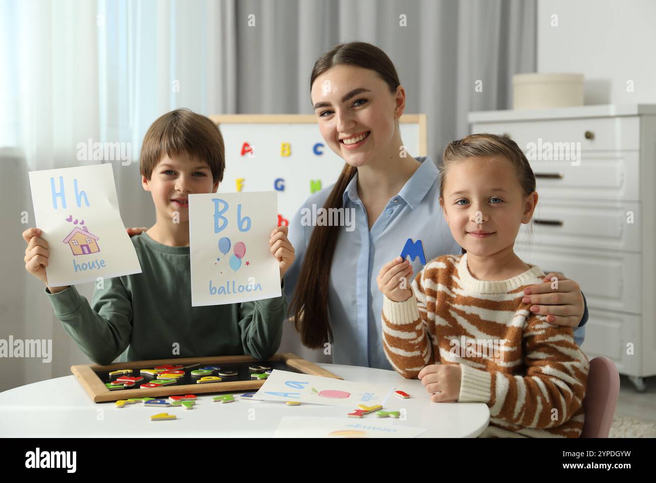 Speech therapist teaching little kids alphabet with magnetic letters ...
