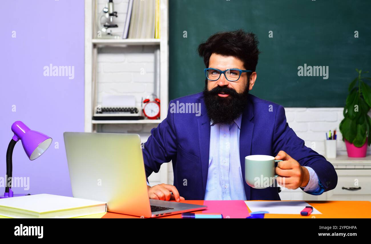 Smiling male teacher or university professor sitting at desk in ...