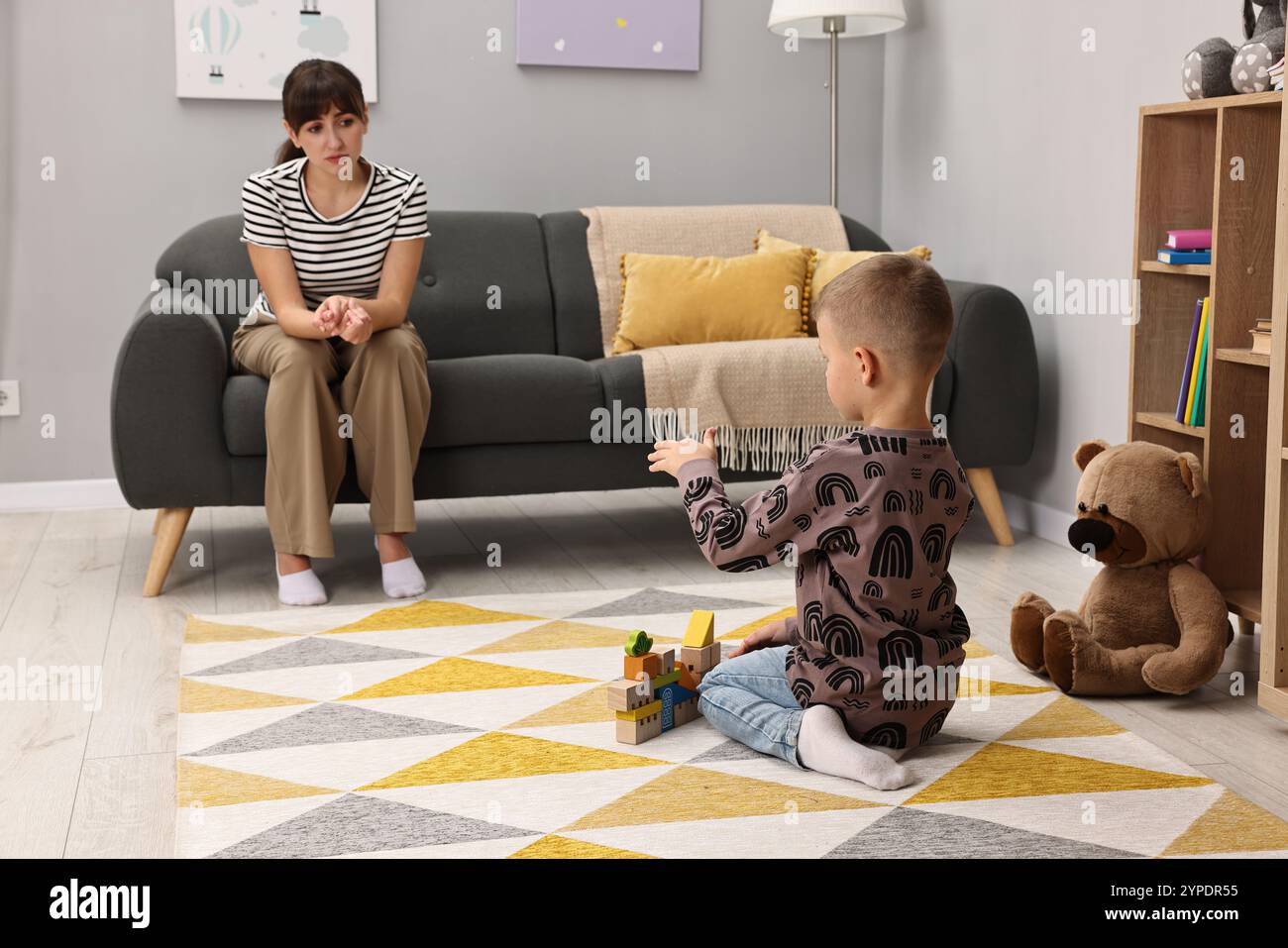 Psychologist observing little boy playing in autism treatment center ...
